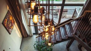 Uma escadaria com corrimão de metal e luminária pendente com lâmpadas aparentes.