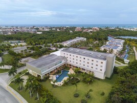 Um hotel com piscina, rodeado por vegetação e vista para o oceano.