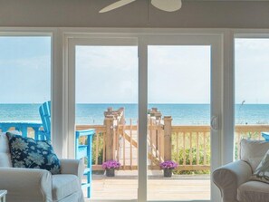 Quarto com vista para o oceano através de grandes portas de vidro deslizantes.