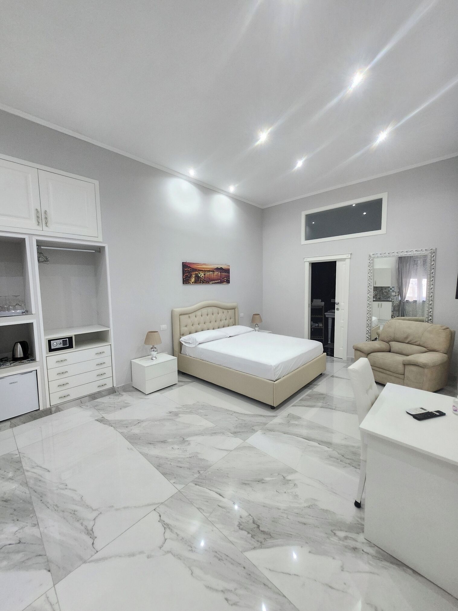 Quarto moderno com cama, escrivaninha, cadeira, guarda-roupa e banheiro.