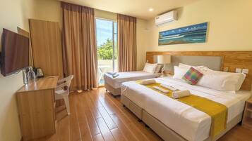 Quarto de hotel com duas camas, uma escrivaninha, uma cadeira, uma televisão e um quadro com uma paisagem de praia.