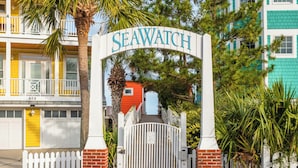 Uma entrada com portão, uma placa com a inscrição 'SEAWATCH' e um muro de tijolos.