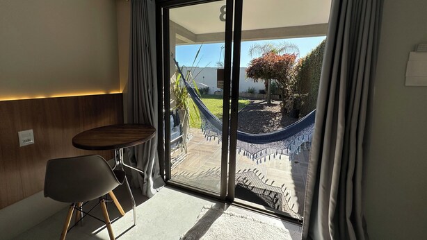 Quarto moderno com porta de vidro deslizante para área externa com rede e uma árvore.