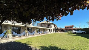 Um edifício moderno com um pátio coberto, um gramado e um carro estacionado.