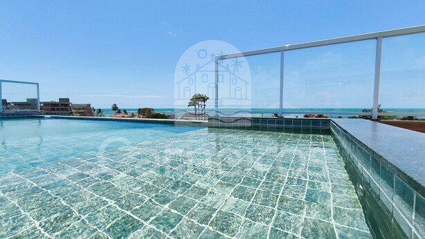 Piscina com água cristalina, guarda-corpo de vidro e vista para o oceano.