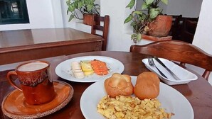 Uma mesa de jantar com pratos de comida, uma xícara de café e talheres.