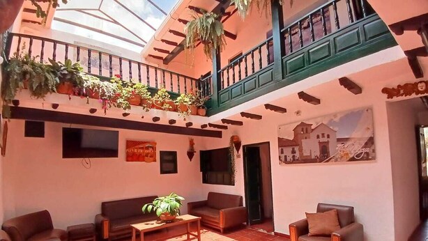 Ampla sala de estar com teto alto, varanda com plantas e um mural na parede.