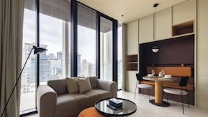 Quarto de hotel moderno com sofá, mesa redonda e espaço para refeições.
