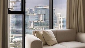 Sala de estar moderna com sofá e uma janela ampla com vista para a cidade.