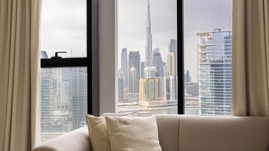Sala de estar com uma grande janela que dá para uma vista urbana com edifícios altos.