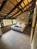 Um quarto espaçoso com uma cama grande, um ventilador de teto e vista para o exterior.