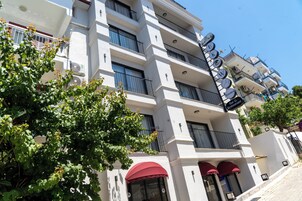 Um edifício de vários andares com sacadas, um toldo vermelho e uma placa indicando um restaurante.