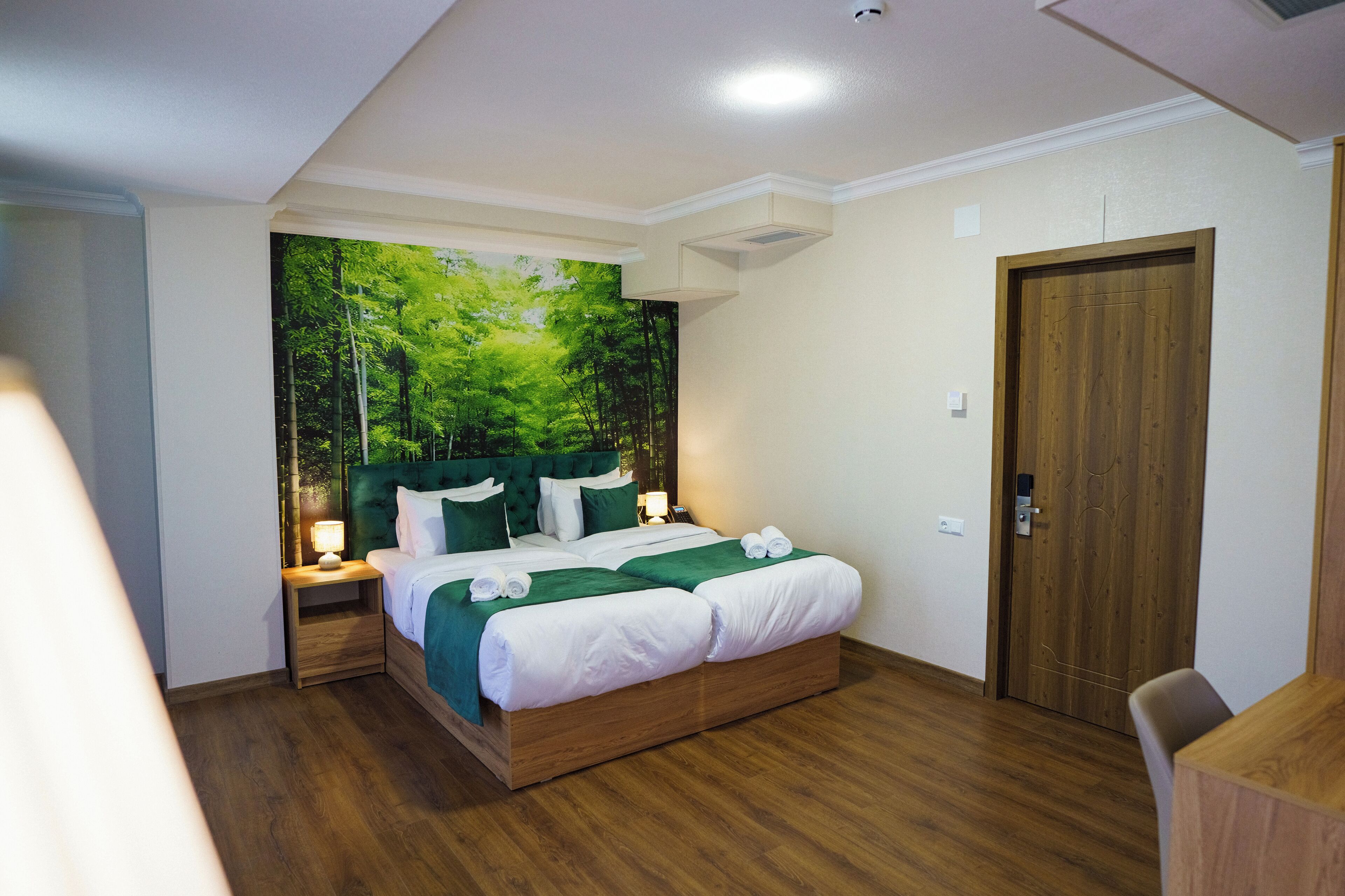 Quarto de hotel com uma cama grande, uma mesa de cabeceira, uma escrivaninha e uma porta.