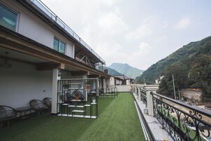 Terraço no telhado com grama sintética, mobiliário de exterior e vista para uma paisagem montanhosa.