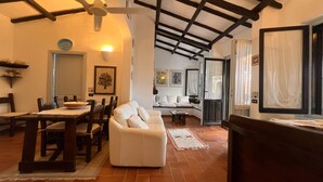 Ampla sala de estar com mesa de jantar, sofá e ventilador de teto.