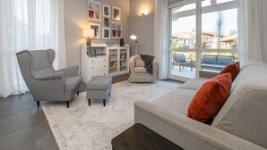 Uma sala de estar moderna com sofá, poltronas, mesa de centro e estante. Há uma janela grande que oferece vista para o exterior.