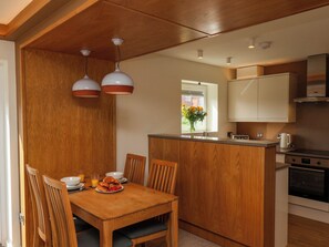 Uma cozinha moderna com armários de madeira, uma ilha central e uma área de jantar com mesa e cadeiras de madeira.