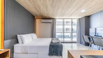 Quarto de hotel moderno com cama, escrivaninha e uma grande janela com vista para a cidade.