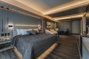 Quarto moderno com uma cama grande, luminárias de cabeceira, uma escrivaninha e um espaço de estar.