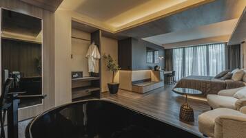 Quarto de hotel moderno com uma cama grande, um sofá, uma escrivaninha e uma cadeira preta.