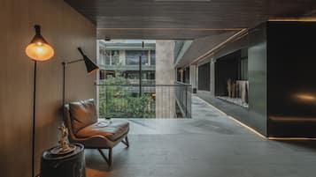 Interior moderno com um sofá de couro, uma luminária de chão e vista para um edifício com varanda.