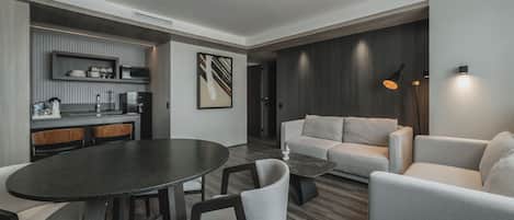 Uma sala de estar moderna com uma mesa de jantar redonda, dois sofás e uma área de cozinha com micro-ondas.