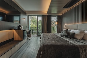 A modern bedroom with a large bed, a desk, and a TV.