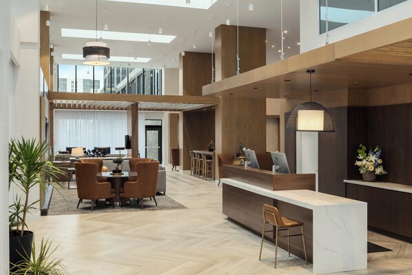 Um hall amplo com balcão de recepção, área de estar e escada que dá acesso aos andares superiores.