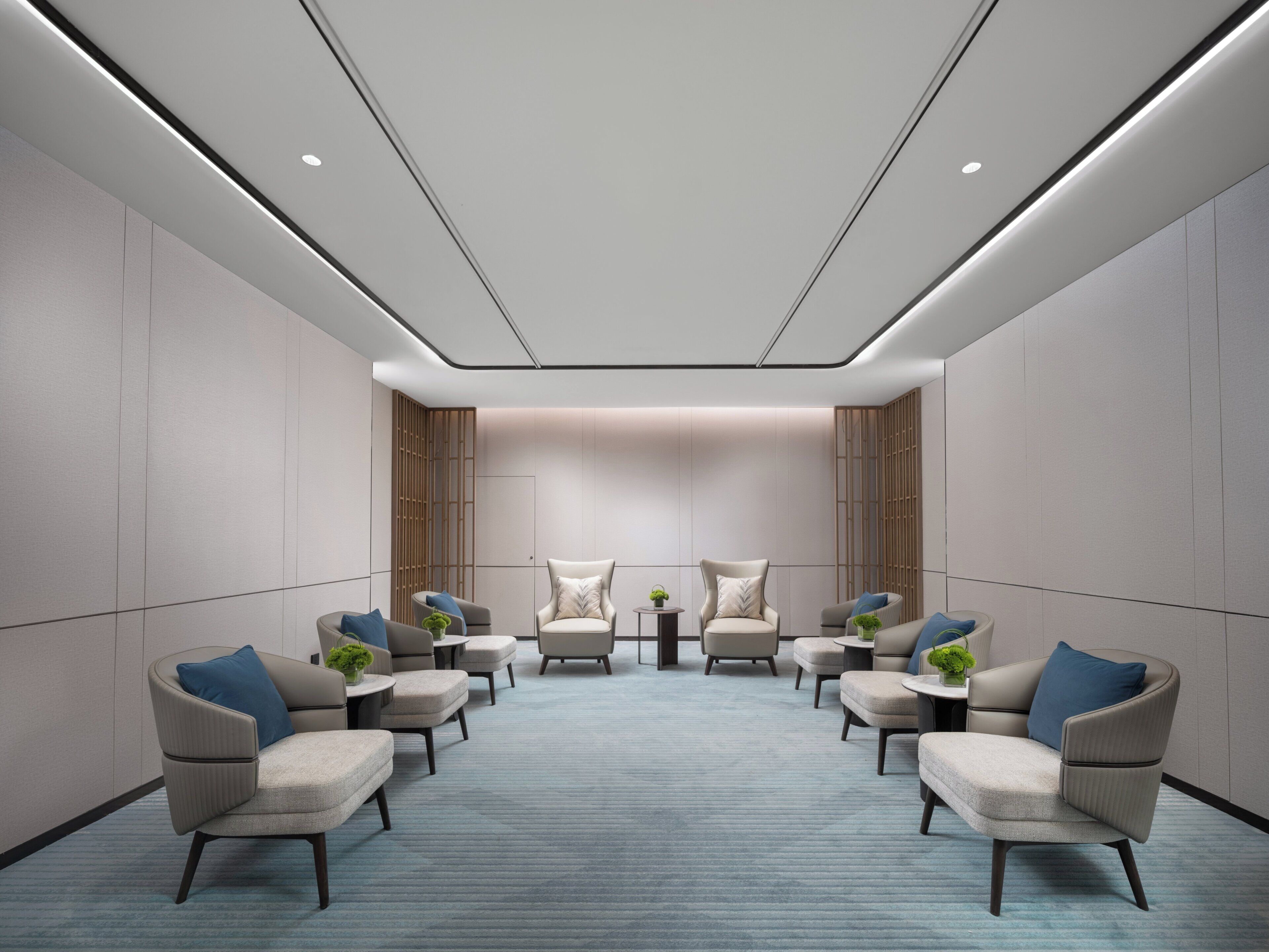 Uma sala de conferências moderna com uma mesa comprida e várias cadeiras, piso coberto por carpete e esquema de cores neutras.