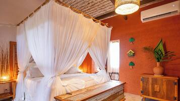 Quarto com cama, luminária pendente, ar condicionado fixado na parede e tapete tecido.