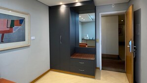 Quarto moderno com um guarda-roupa, uma pintura abstrata emoldurada e soalho de madeira.