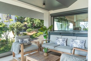 Uma varanda com sofá, cadeiras e uma mesa de madeira.
