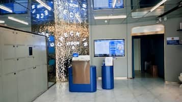Uma área de recepção com parede de vidro, balcão de atendimento e painel de informações digital.