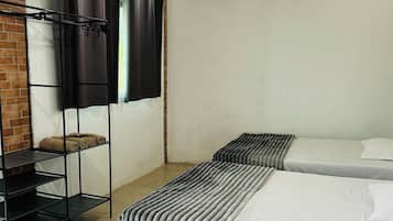 Quarto com beliches, prateleira com toalhas, televisão na parede e luminária pendente.
