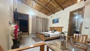 Quarto com cama, móveis de madeira, mesa de jantar e um vaso com flores.