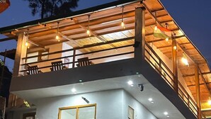 Um edifício de dois andares em construção, com varanda e uma grande janela no andar térreo.