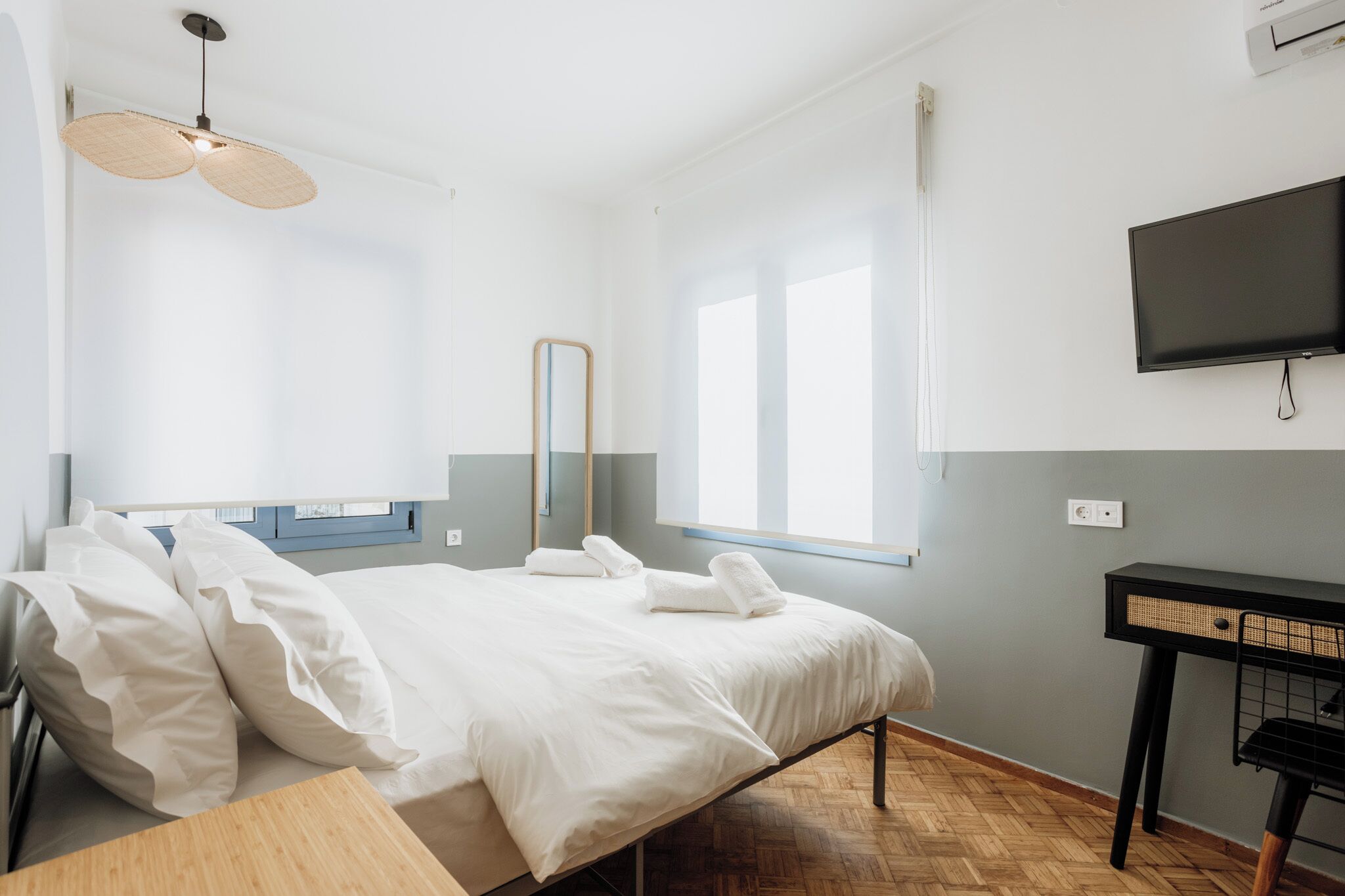 Quarto de hotel moderno com cama, escrivaninha, televisão e uma janela grande.