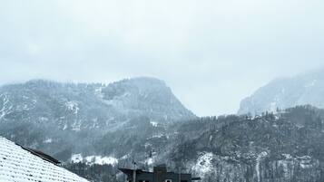 Paisagem montanhosa com picos cobertos de neve e um edifício com telhado inclinado.