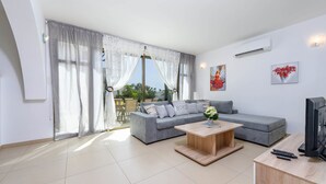 Uma sala de estar moderna com um sofá cinzento, uma mesa de centro de madeira e um suporte para TV.