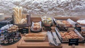 Vitrine de padaria com diversos pães e doces, incluindo brioche e focaccia, com etiquetas identificando os tipos.