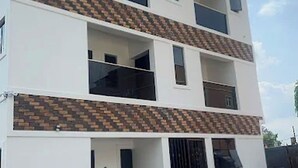 Um edifício com vários andares, fachada plana, janelas grandes e detalhes em tijolo na base.