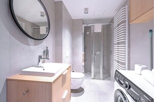 Uma casa de banho moderna com lavatório, sanita e zona de duche.