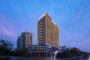 Um hotel moderno com design vertical marcante, vários andares e entrada bem iluminada.
