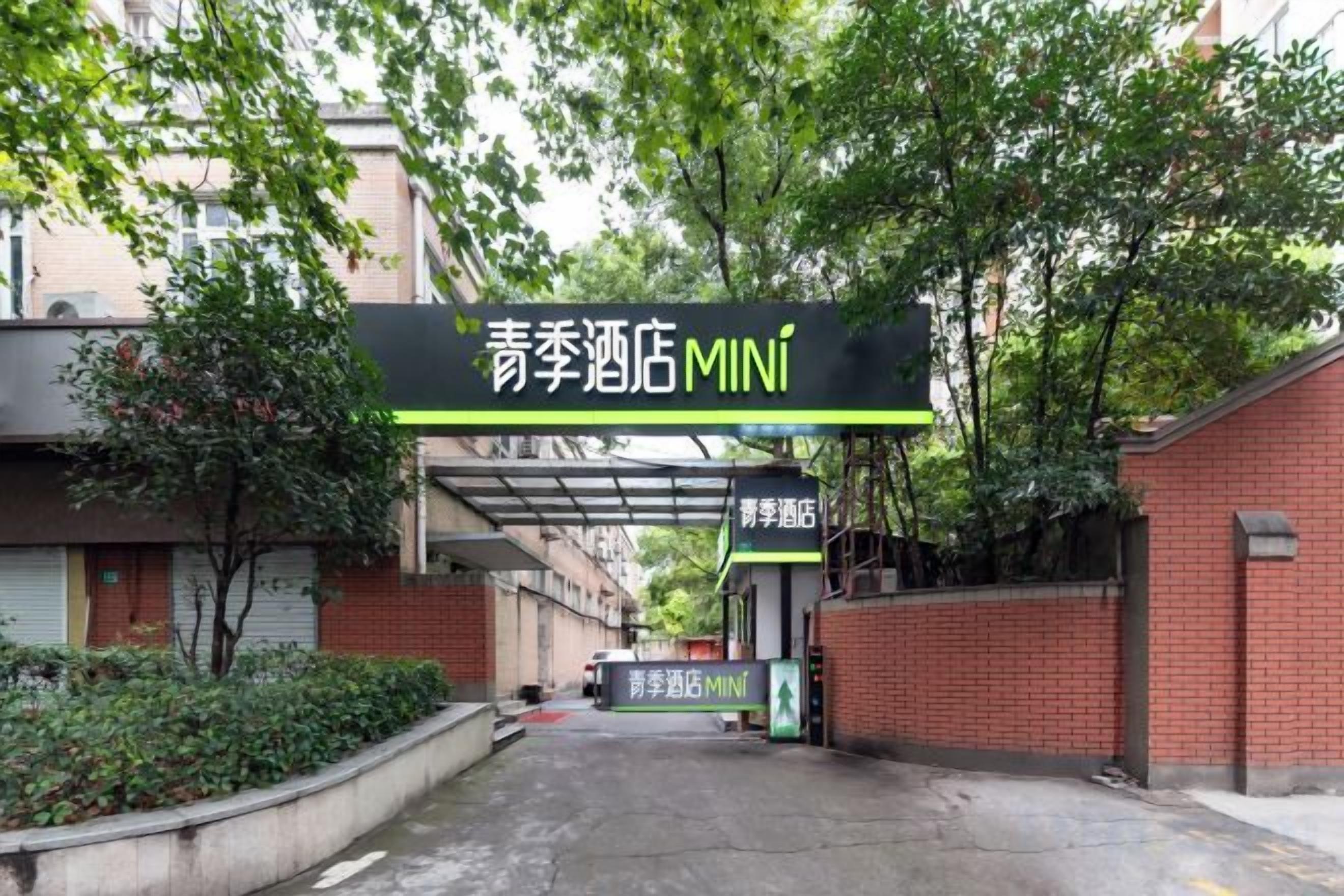 Entrada de um hotel com uma placa que diz '青季酒店MINI'.
