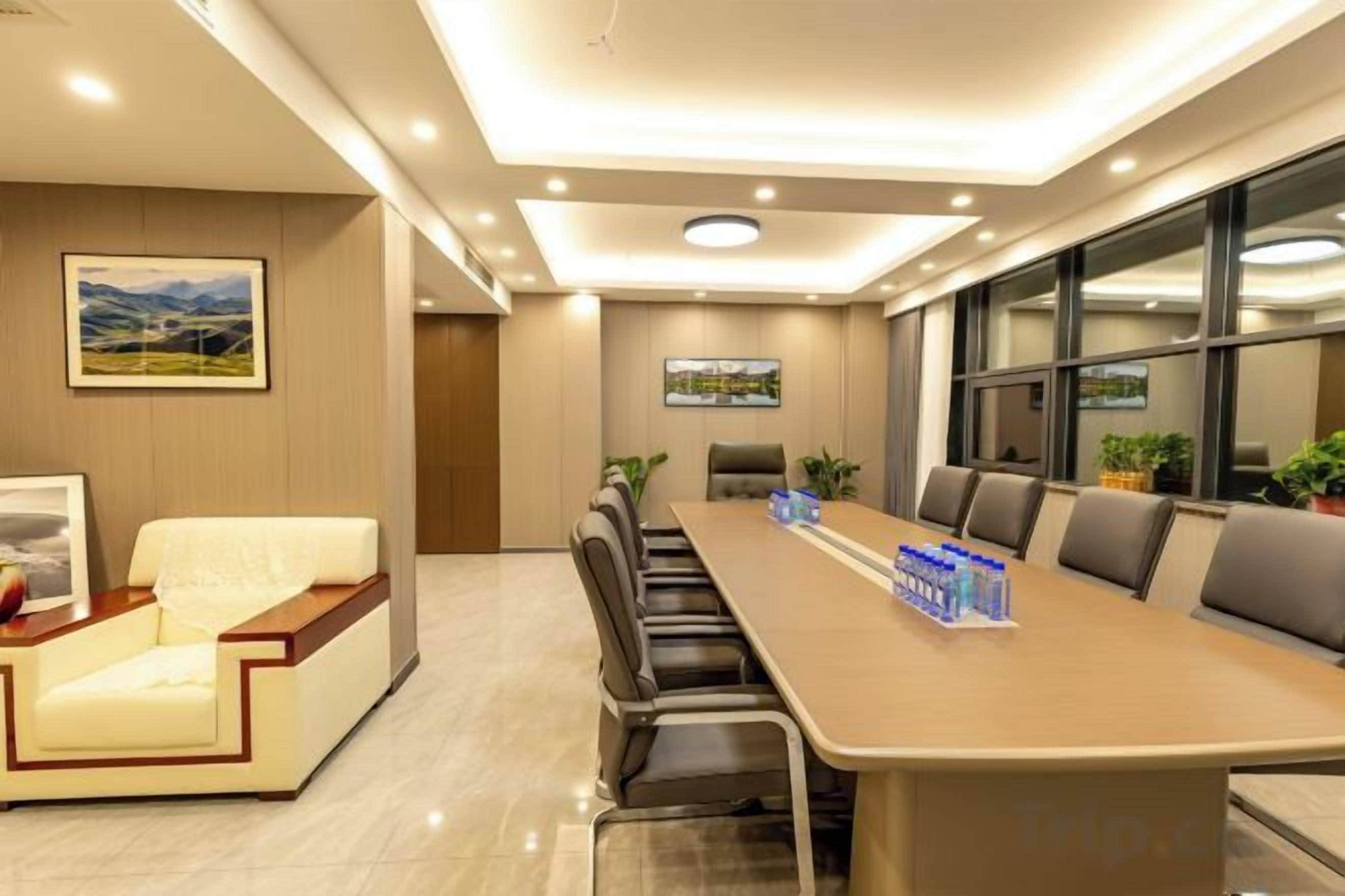 Uma sala de conferências com uma mesa comprida, cadeiras e um sofá.