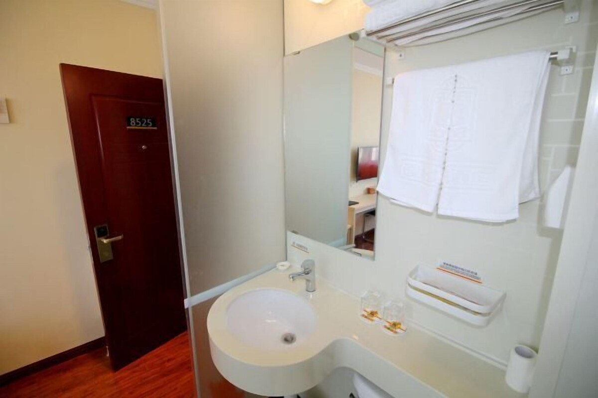 Casa de banho de hotel com lavatório branco, espelho e porta-toalhas.