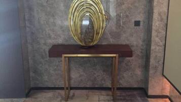 Um quarto com parede texturizada, um banco de madeira com um objeto decorativo dourado em cima e um tapete estampado no chão.