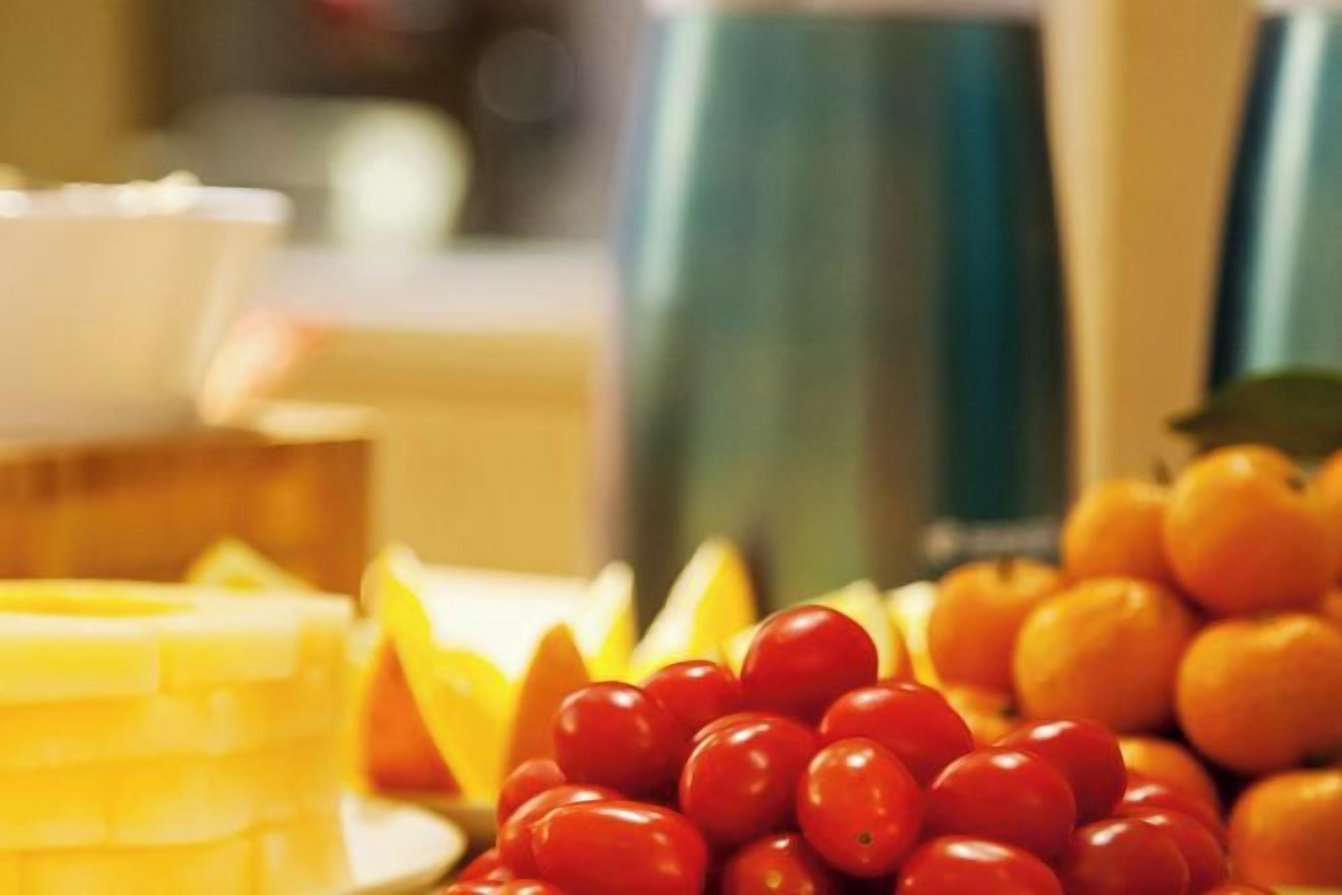 Uma mesa com diversas frutas, incluindo laranjas e tomates.