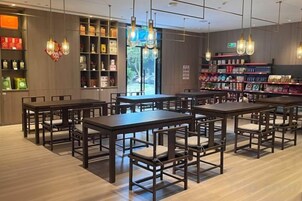 Interior de restaurante com várias mesas e cadeiras, prateleiras com diversos objetos e luminárias pendentes.