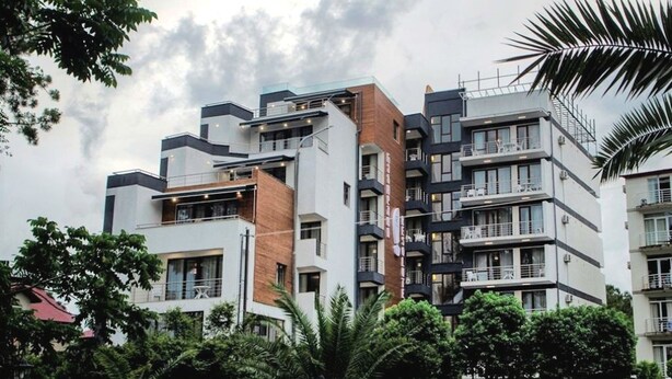 Um edifício residencial com várias andares, varandas, grandes janelas e design arquitetônico moderno.